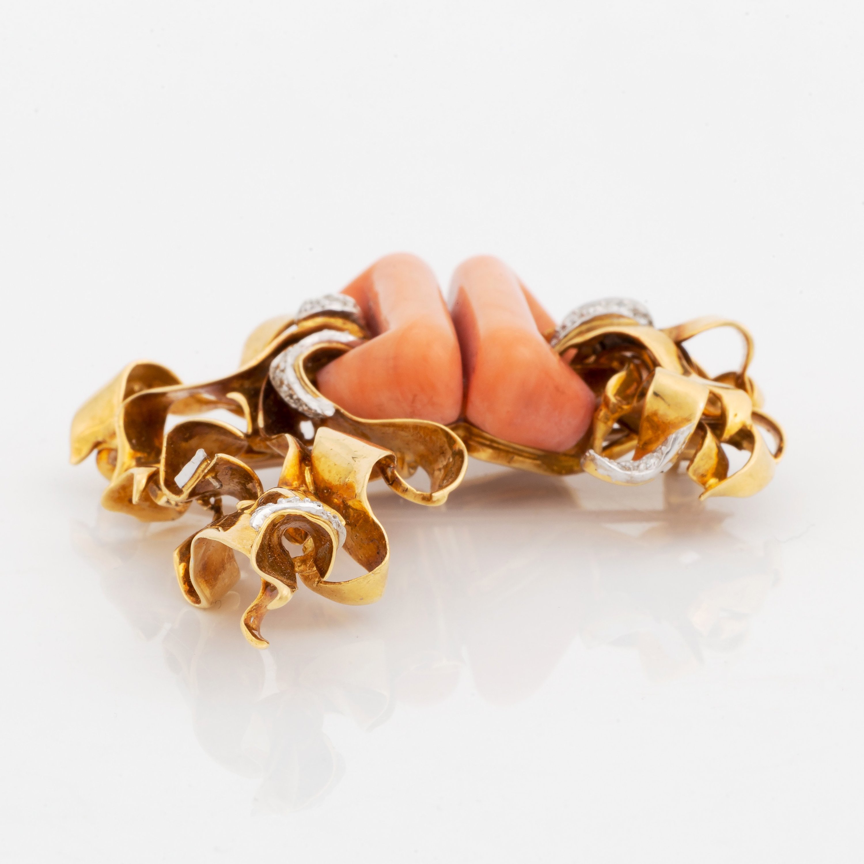 A Kutchinsky brooch in 18K gold set with coral and round brilliant-cut ...