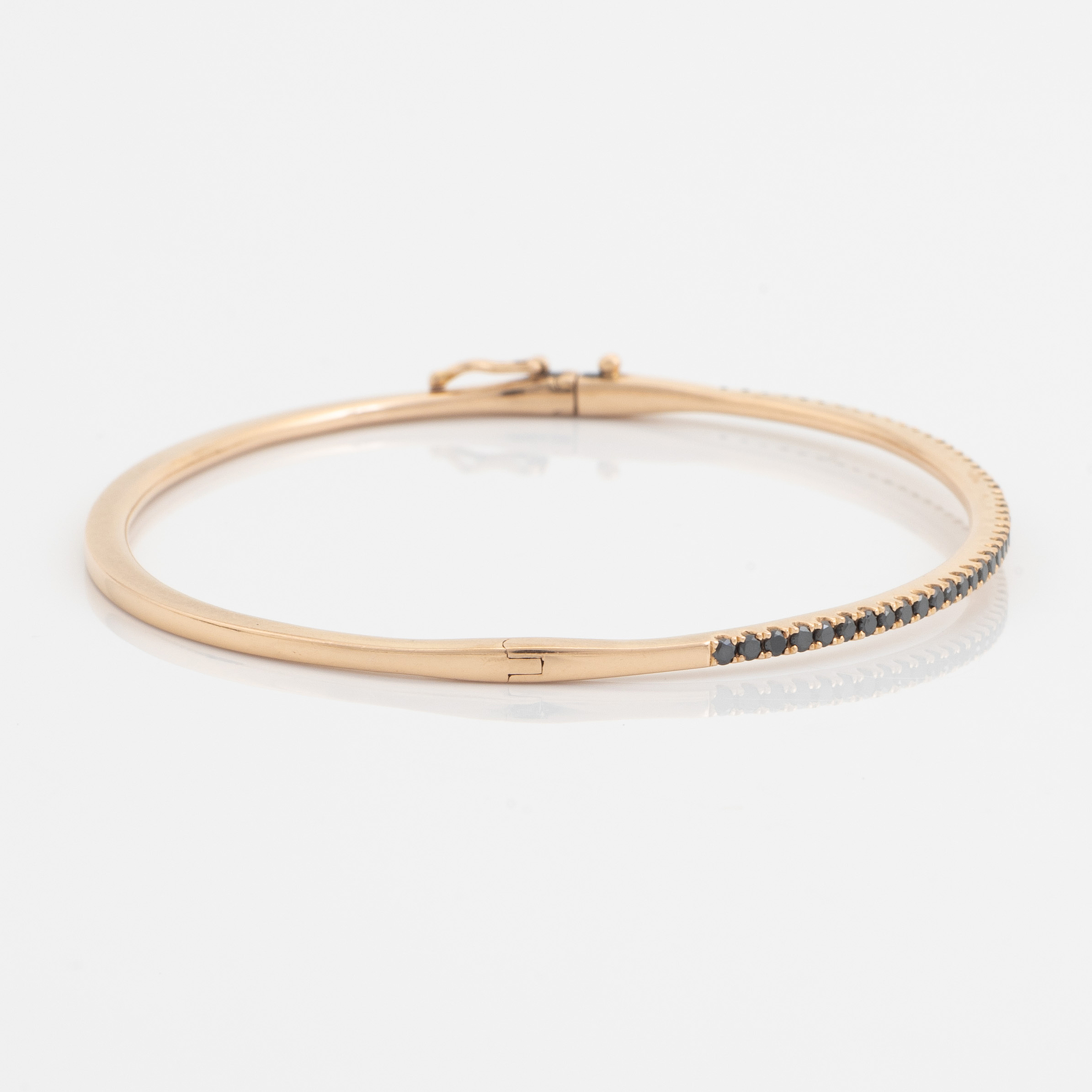 An 18K rose gold bangle set with round brilliant-cut black diamonds ...