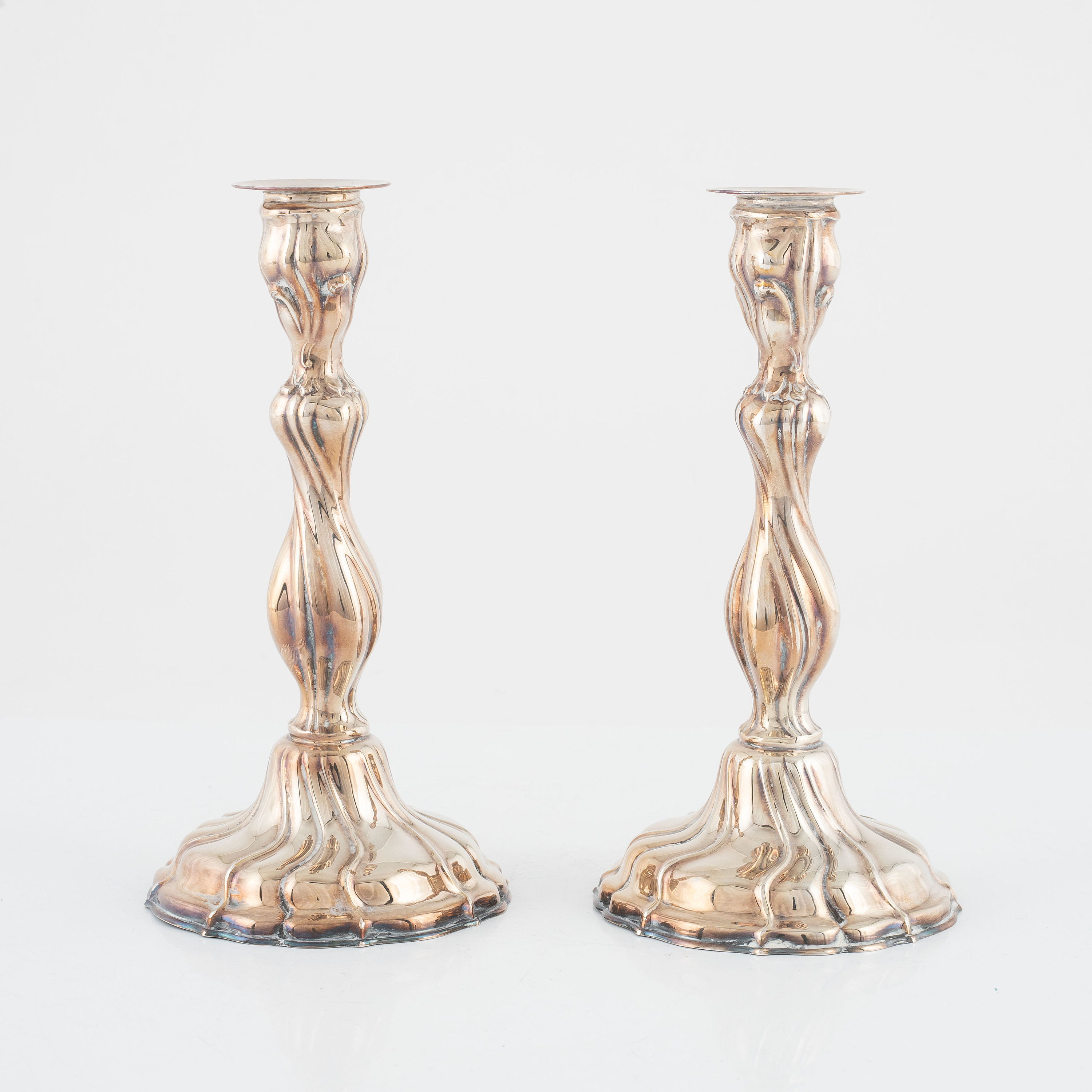 A pair of German Rococo style silver candlesticks, 20th Century, with ...