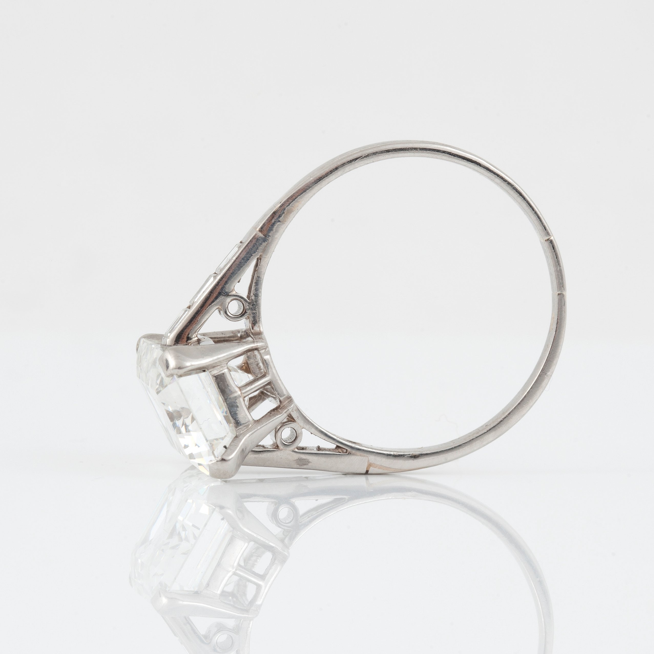 A 5.53 ct emerald-cut diamond, F/VVS2, ring. Center stone flanked by 6 ...