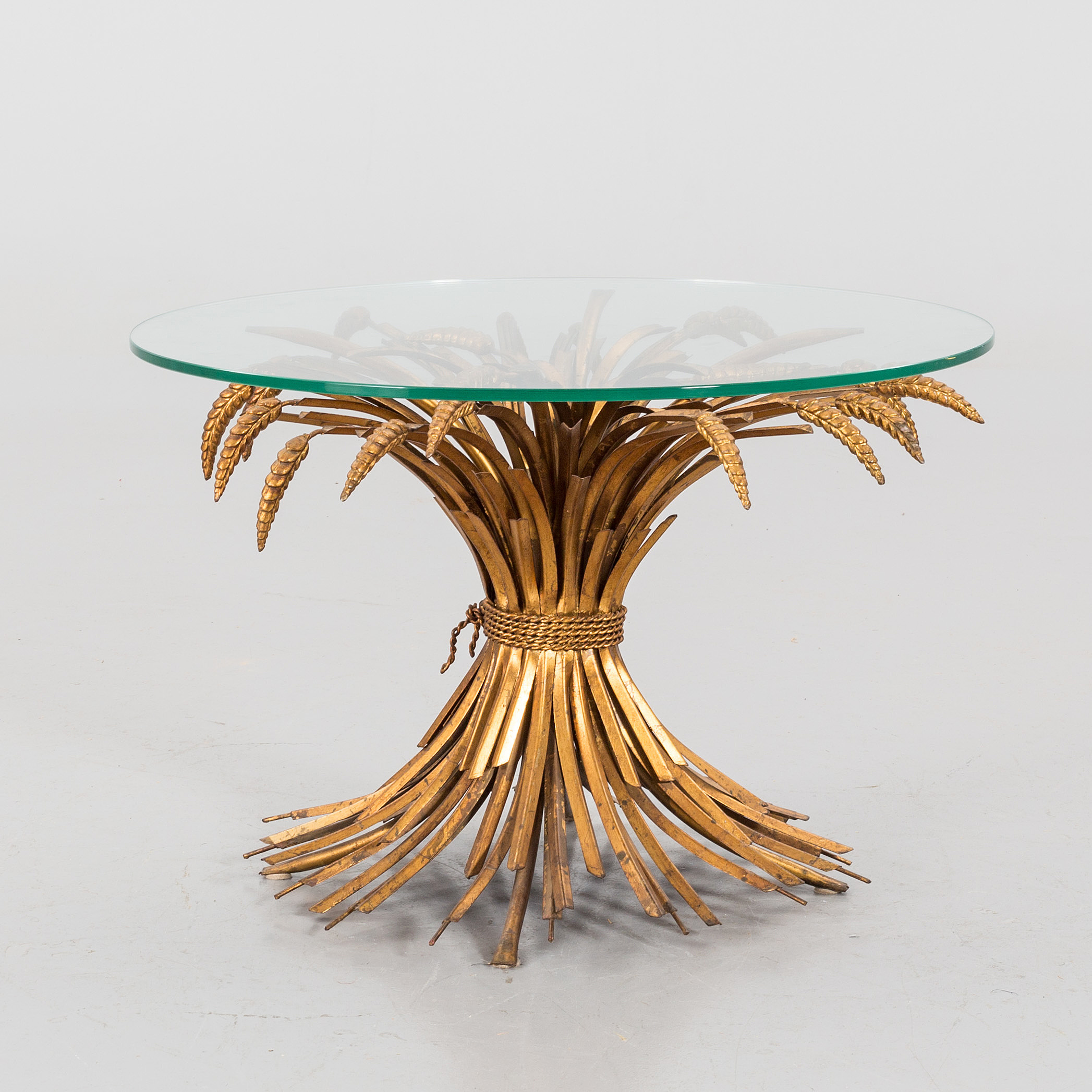 A HANS KÖGL ROUND GLAS AND GUILT METAL COFFEE TABLE. - Bukowskis