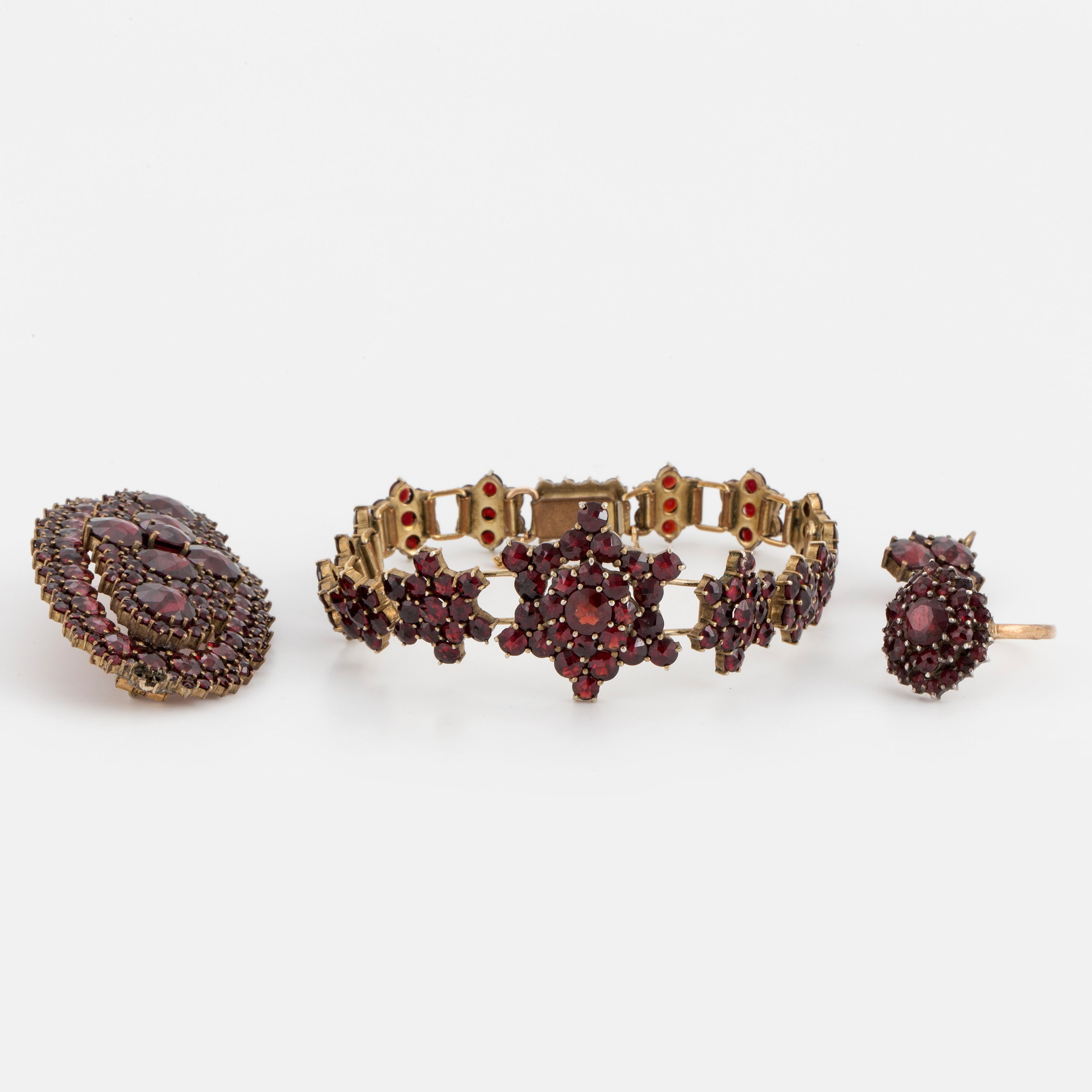 BROSCH, ARMBAND, RING samt HÄNGE med fasettslipade granater. - Bukowskis