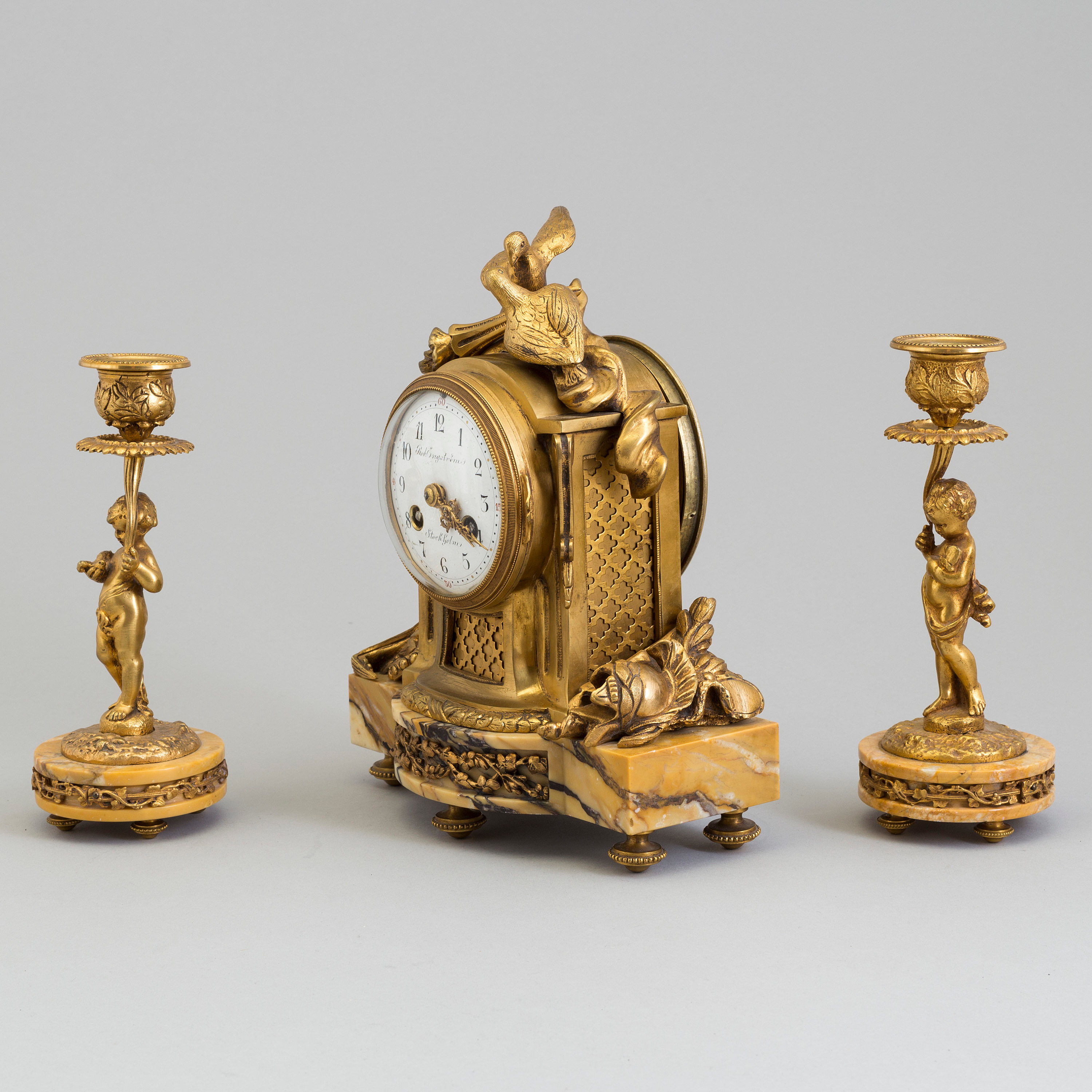 A mantle clock and a pair of candlesticks, early 20th century. - Bukowskis